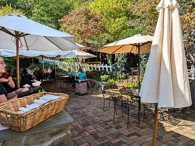 The secret garden revealed: a brick-paved oasis where umbrellas create islands of shade and flowering plants transform eating outdoors into a mini-vacation.