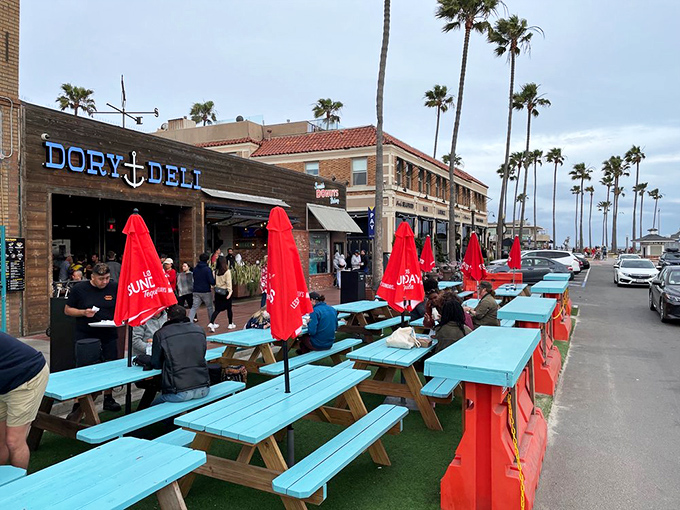 Turquoise picnic tables under California palms—because some meals deserve ocean breezes and the soundtrack of crashing waves.