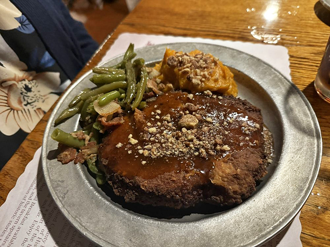 The pork chop arrives glistening with savory gravy and topped with crushed nuts. Those green beans aren't just a side—they're vegetables with purpose.