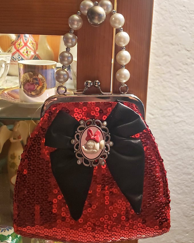A sequined Minnie Mouse purse with pearl handle—Disney glamour meets thrift store magic. Childhood nostalgia packaged as functional fashion.