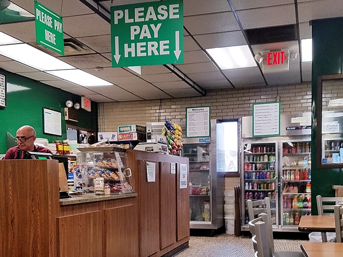 The "Please Pay Here" sign hangs above the register—a reminder of simpler times when transactions were straightforward and desserts waited in glass cases.