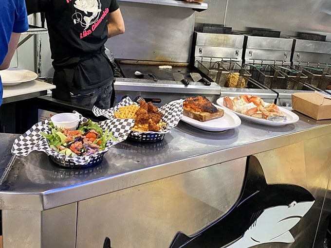 The serving line isn't just a food station—it's where ocean bounty meets culinary artistry. That shark silhouette knows exactly what's about to happen.
