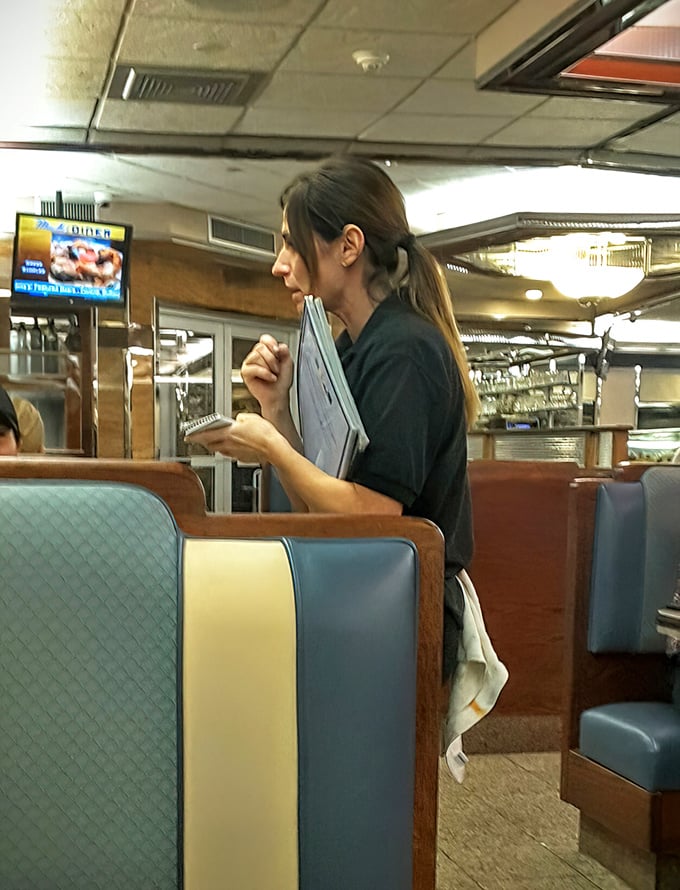 The waitstaff moves with practiced efficiency—order pads at the ready, navigating the dance of service that keeps a beloved diner running smoothly.
