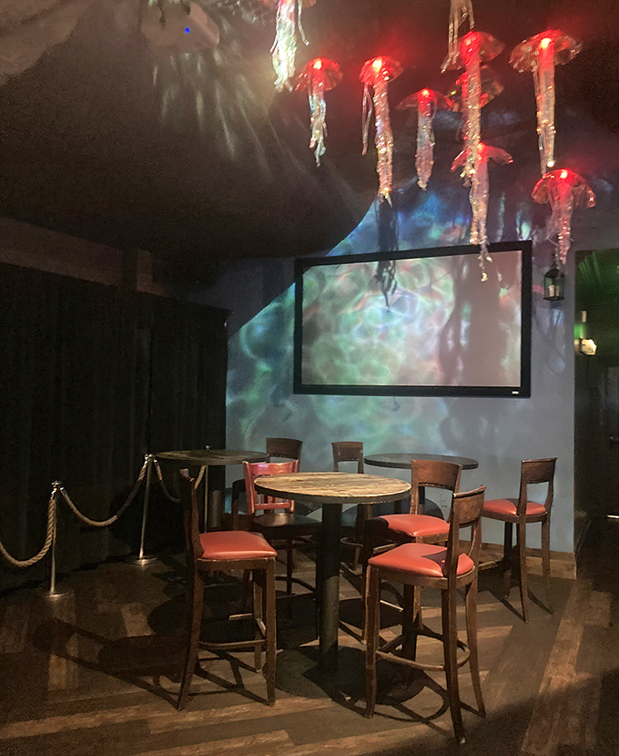 A cozy corner table awaits beneath glowing jellyfish – dinner and a show, underwater-style.