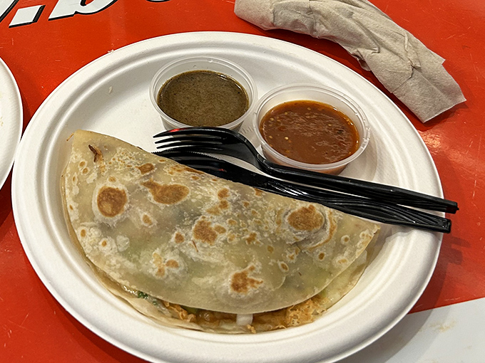 A perfectly browned tortilla cradling its precious cargo, flanked by two salsas—one for courage, one for comfort.