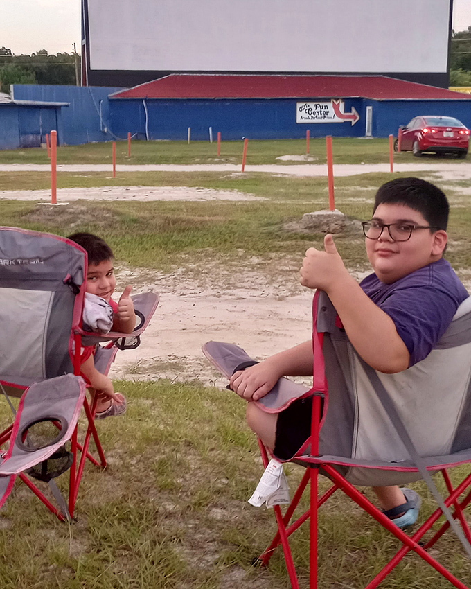 Two young moviegoers give the universal thumbs-up of approval—the drive-in's ultimate critics who know comfortable chairs and good sightlines are everything.