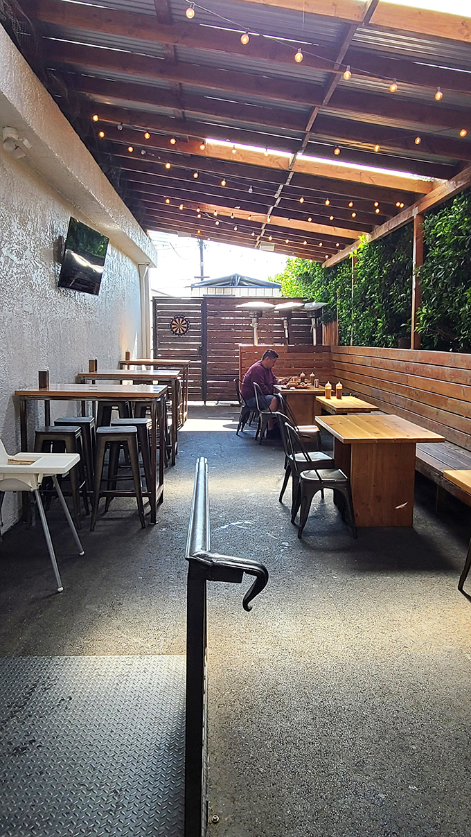 The string lights and wooden benches create an outdoor oasis where strangers become friends united by the universal language of barbecue.