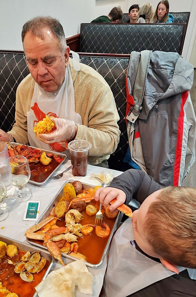 The universal language of seafood brings generations together. Plastic gloves, bibs, and focused expressions—the uniform and demeanor of serious seafood enthusiasts.
