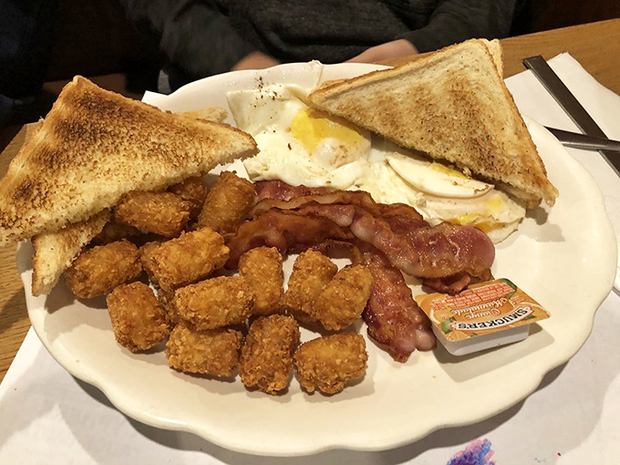The breakfast sampler plate—where eggs, bacon, and tater tots form a golden triangle of morning perfection.
