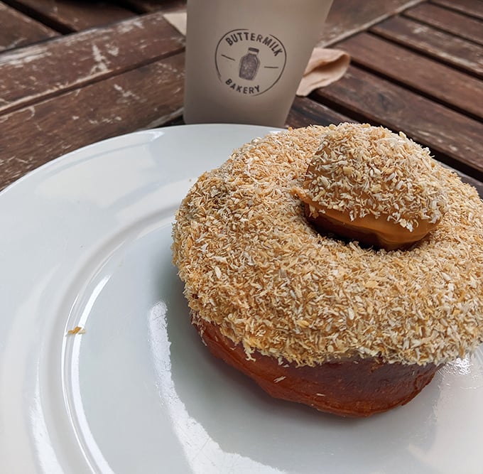 This coconut-dusted donut isn't just breakfast—it's a tropical vacation for your mouth. The coffee cup stands by, ready to wash the paradise down.