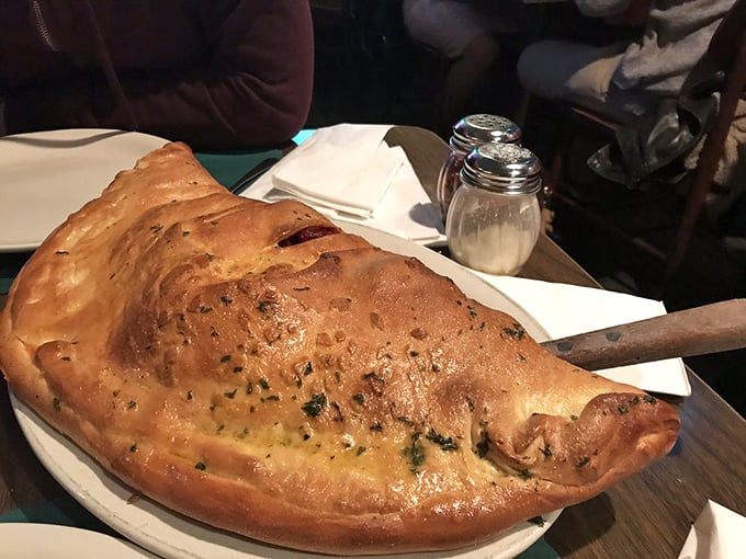 The calzone arrives like a golden continent on your plate – a hand-formed masterpiece that makes you wonder if you should have brought reinforcements for this meal. 