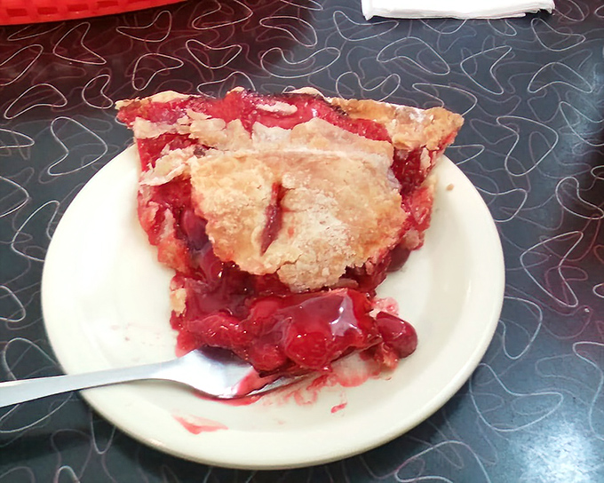 Cherry pie that bleeds ruby red onto the plate—not a dessert so much as a declaration of fruit's divine purpose.