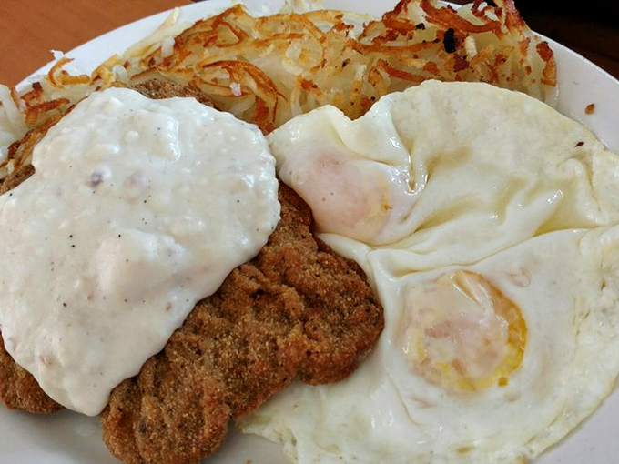 Country fried steak with gravy alongside sunny-side-up eggs creates the perfect breakfast trinity—crispy, creamy, and runny in harmonious balance.
