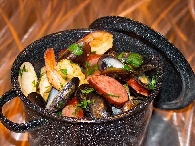 A black pot brimming with seafood treasures—mussels, shrimp, and sausage swimming in a broth worth sopping up with every available bread morsel.