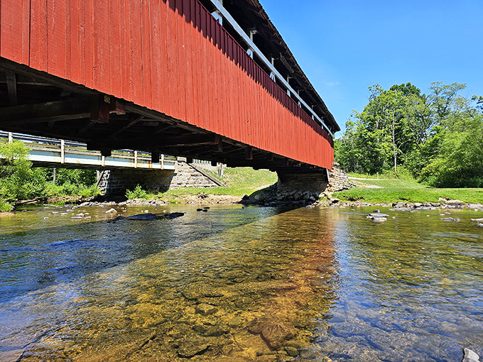 Crystal clear waters reflect the bridge's timeless silhouette, creating a perfect mirror image that doubles the visual impact of this historic treasure.