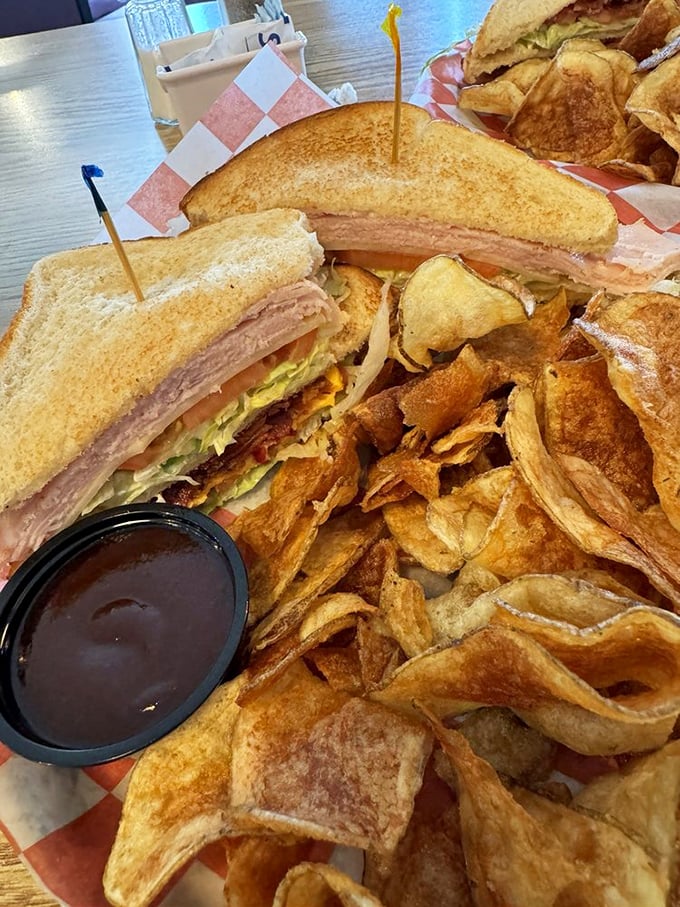 Club sandwich architecture that would make Frank Lloyd Wright proud. Those homemade chips aren't just sides—they're main attractions.