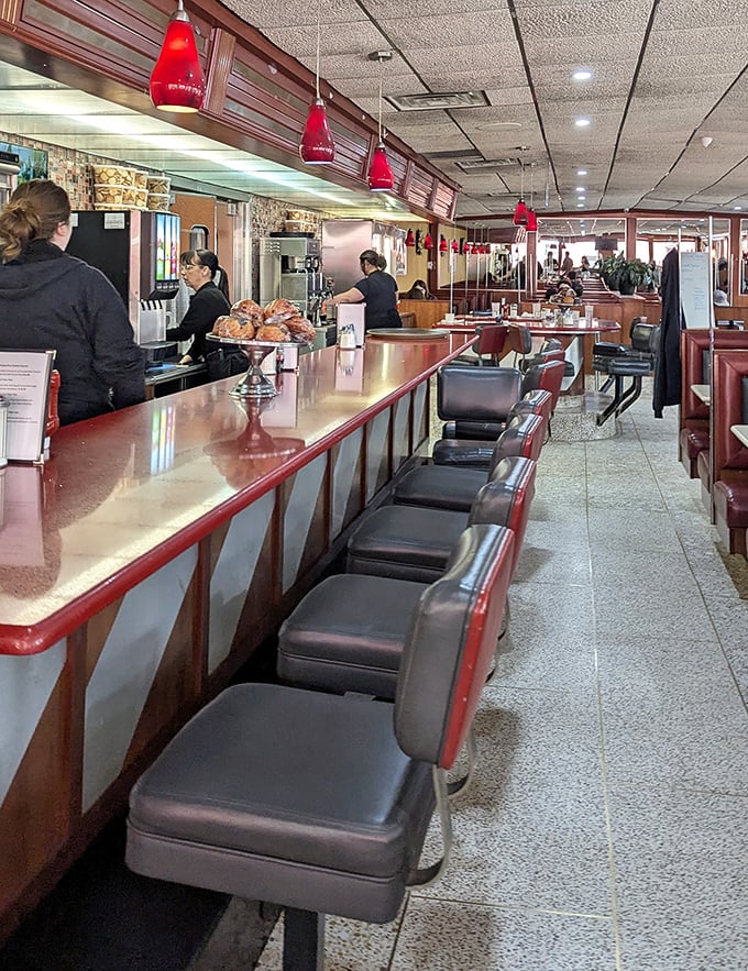 The counter seats—where solo diners become regulars and servers become therapists. Red pendant lights add that classic diner glow.