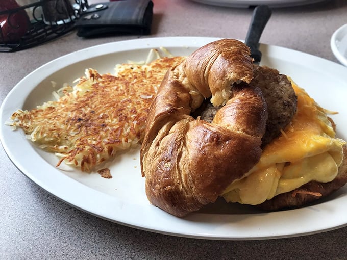 A croissant breakfast sandwich that's living its best life, accompanied by hash browns that achieved the perfect crisp-to-tender ratio.