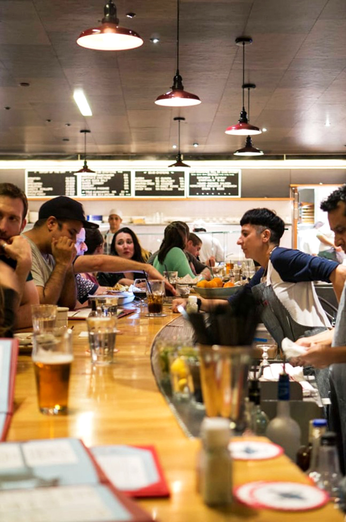 The communal counter experience—where strangers become friends united by the universal language of "pass the hot sauce, please."