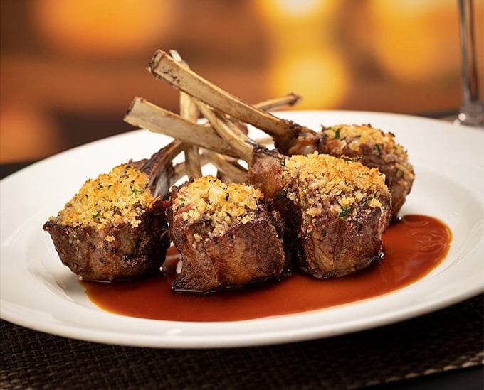 Lamb chops wearing their breadcrumb best. These aren't just chops—they're tiny meat lollipops for sophisticated grown-ups.