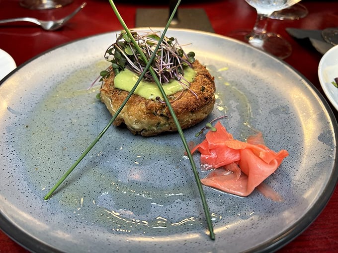The Dungeness crab cake arrives like an edible sculpture, its golden crust hiding sweet meat within, accompanied by pickled ginger that cuts through richness.