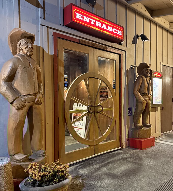 Wooden cowboy sentinels guard the entrance, silently judging if you're worthy of the beef bounty that awaits inside.