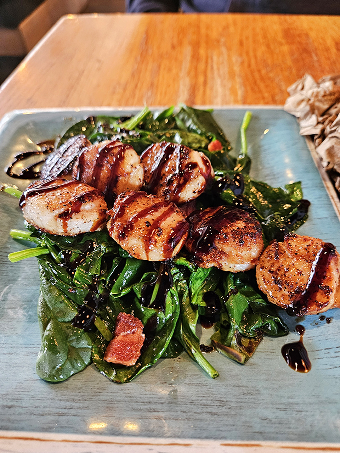 Perfectly seared scallops atop fresh greens—a dish that showcases the kitchen's finesse beyond frying. Those caramelized edges contain universes of flavor.