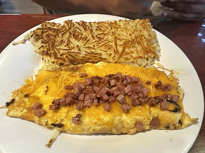 An omelet that knows how to dress for breakfast – golden cheese blanket, ham confetti, and a hash brown companion that's achieved crispy perfection.
