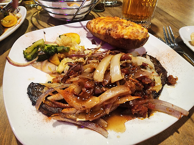 A plate that proves onions and liver were meant for each other—like an odd couple that somehow works perfectly. That baked potato is the reliable sidekick.