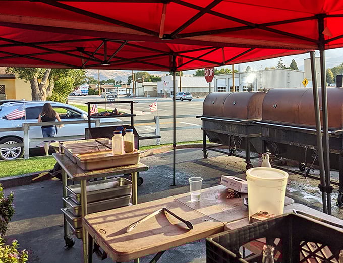 Under the red tent, barbecue alchemy happens. Those smokers aren't just cooking equipment – they're time machines to flavor country.