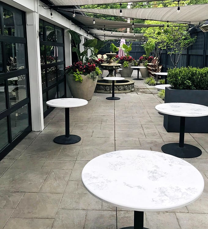 The outdoor patio offers an urban oasis—string lights overhead, greenery all around, and tables awaiting your reservation. Al fresco elegance.