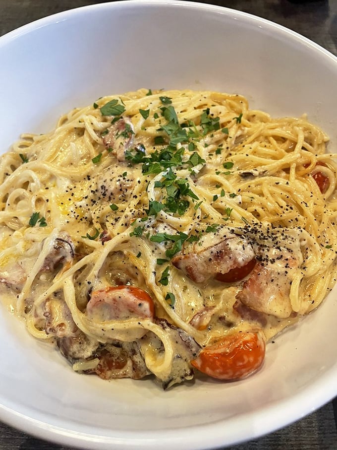 Carbonara that's achieved the pasta dream—each strand perfectly coated in silky sauce with cherry tomatoes providing bright counterpoints to richness.
