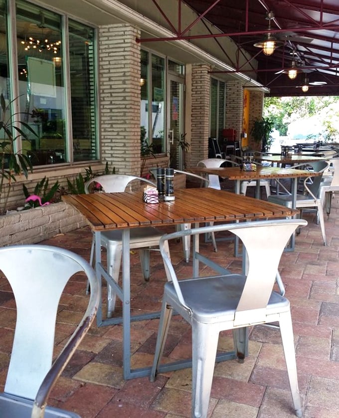 The patio seating offers a perfect Florida alfresco dining experience—where brick, wood, and metal create an industrial-chic vibe under the gentle protection of palm fronds. 