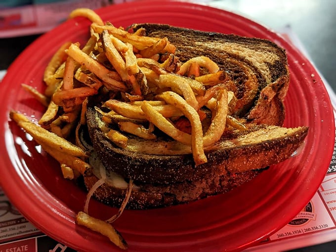The patty melt, that brilliant marriage of burger and grilled cheese, arrives with a tangle of fries that demands to be shared.