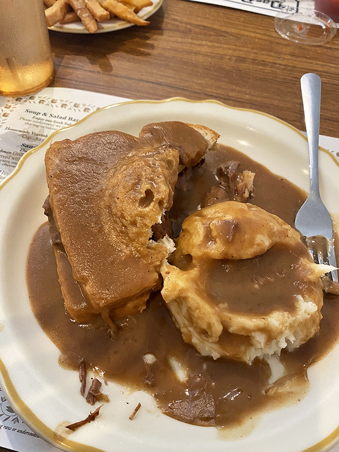 Hot roast beef sandwich swimming in gravy—comfort food that doesn't just speak to your soul, it writes it a love letter.