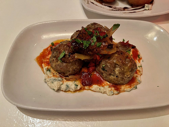 These meatballs aren't just appetizers—they're little ambassadors of flavor perched atop a creamy sea of what must be someone's grandmother's recipe.