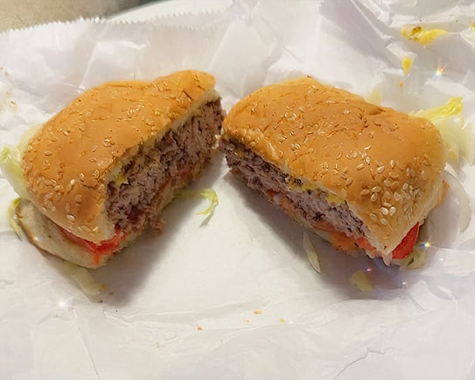 Cross-section evidence of burger perfection—juicy beef cooked just right, melted cheese, and fresh toppings on a sesame seed bun. This is burger science at its finest.