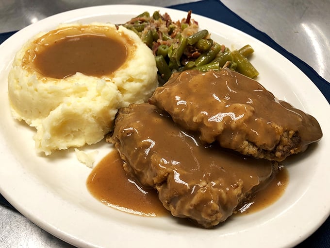Swiss steak swimming in gravy with a mashed potato island—the kind of plate that makes you want to hug the chef and your cardiologist. 