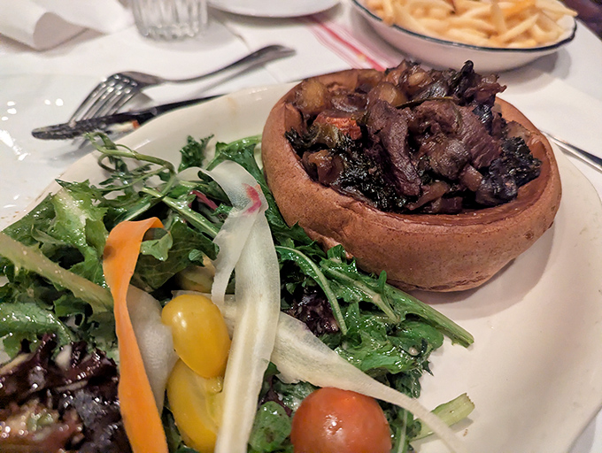 Toad in the hole—a savory Yorkshire pudding filled with tender meat—comes with a side salad that somehow makes you feel virtuous while indulging.