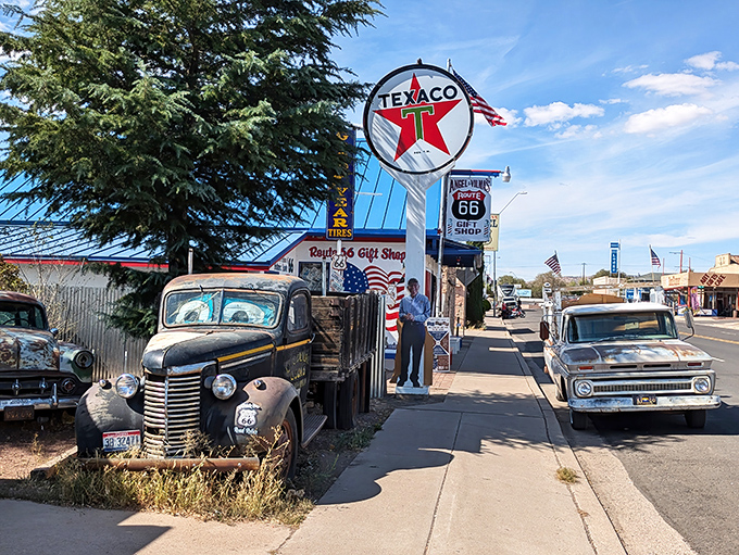 These vintage cars aren't props—they're retired road warriors standing guard outside a fellow Route 66 legend.