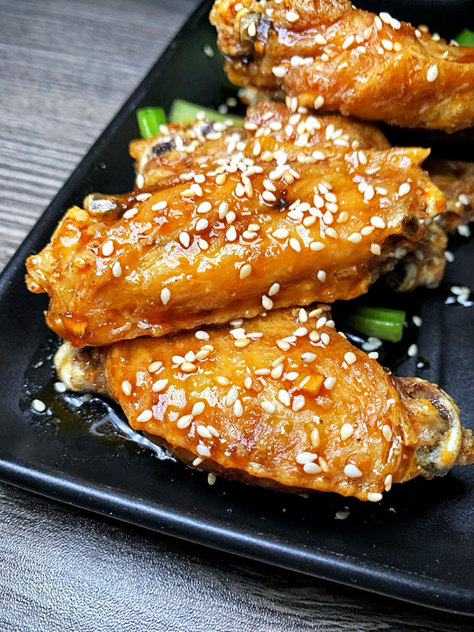Wings where the sesame seeds aren't just garnish—they're little crunchy exclamation points punctuating each bite of sticky-sweet goodness.