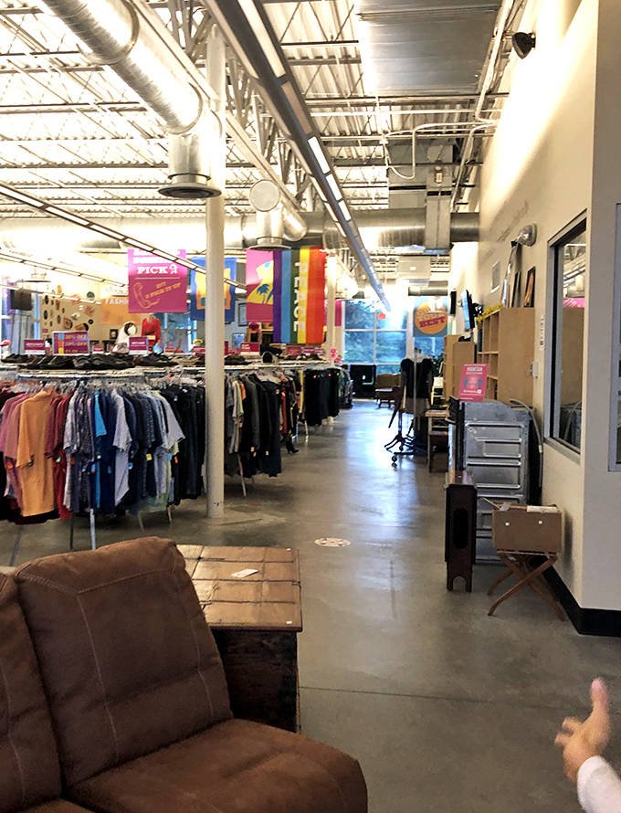 The store's industrial-chic interior features concrete floors and exposed ductwork, creating a modern backdrop for vintage treasures. Comfortable seating invites shoppers to pause and consider.