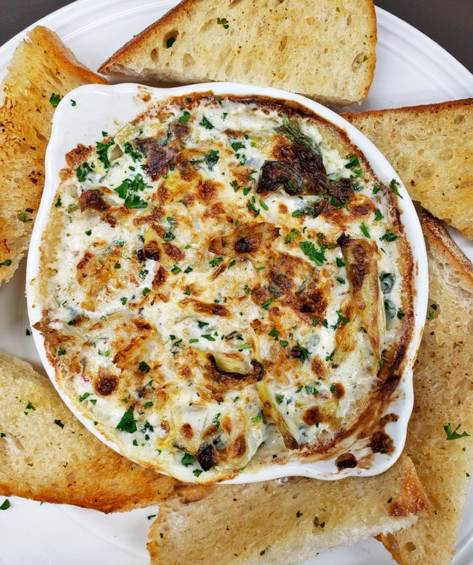 This bubbling artichoke dip isn't just an appetizer—it's a social event. The toast points are merely vehicles for maximum cheese delivery.