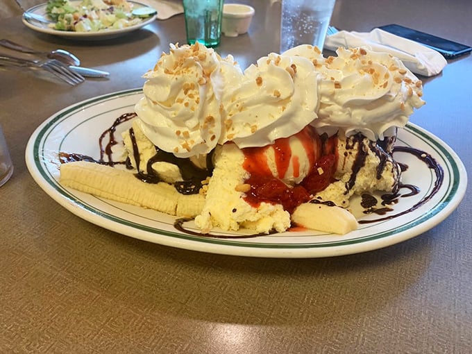 A banana split that doesn't just end your meal—it celebrates it. Those whipped cream peaks, chocolate drizzle, and toasted coconut flakes are pure joy on a plate.
