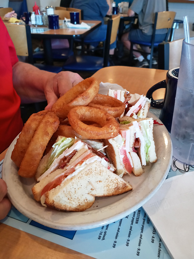 The club sandwich—three layers of architectural brilliance with onion rings that deserve their own Ohio historical marker.