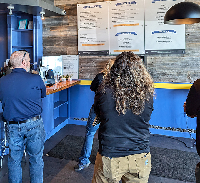 The menu board attracts customers like a burger-scented magnet—notice how everyone's already deciding before they even reach the counter?