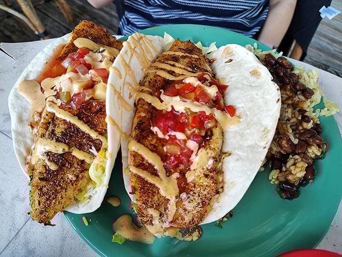 Blackened fish tacos drizzled with sauce and topped with fresh pico—a handheld vacation for your taste buds. The side of black beans and rice isn't just there for moral support.