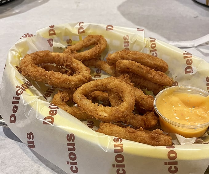 Onion rings that achieve the perfect golden ratio—crispy exterior giving way to sweet, tender onion within. That dipping sauce isn't optional; it's the exclamation point on every bite.