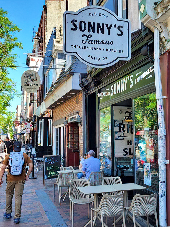 The sidewalk seating scene – where locals and tourists alike perform the sacred Philly ritual of people-watching while devouring cheesesteak perfection.