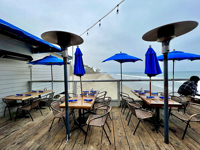 Outdoor dining that puts your feet practically in the sand. Those blue umbrellas aren't just for shade—they're framing perfect Pacific memories.